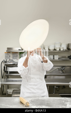Chef throwing pizza dough mid air in commercial kitchen. High quality ...