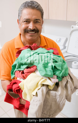 Hispanic man doing laundry holding piggy bank celebrating victory with ...