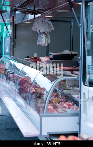 A butcher in a market offers meat for sale from his mobile truck ...