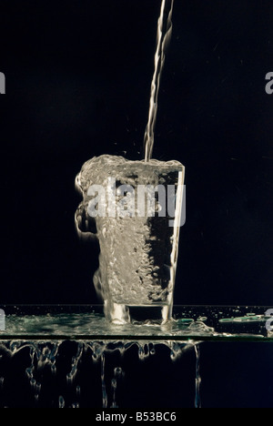 Pouring water into a glass, Overflowing Stock Photo - Alamy