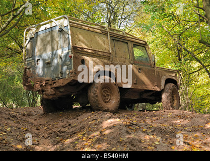 Muddy Land Rover Defender 110 going through deep mud on a forest track ...