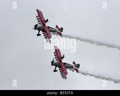 Stunt flying bi-planes with a female wing walker standing on the top ...