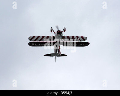 Stunt flying bi-plane with a female wing walker standing on the top ...