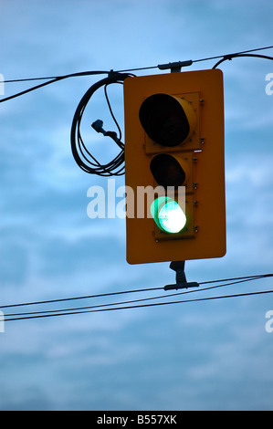 Three red traffic lights hang over the road against the blue sky ...