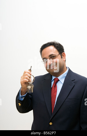 Businessman in suit holding keys with keys graphics around and dark ...