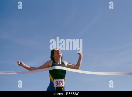 Female runner victorious at the finish line in a track race Stock Photo ...