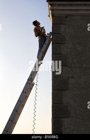 Worker climbing a tall ladder on a building facade in winter Stock ...