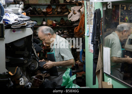 Busy cobbler, shoe repairer, working away in a side street in Barri ...