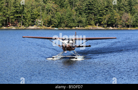 A single engine float plane taxing to the dock on Long Lake New York ...