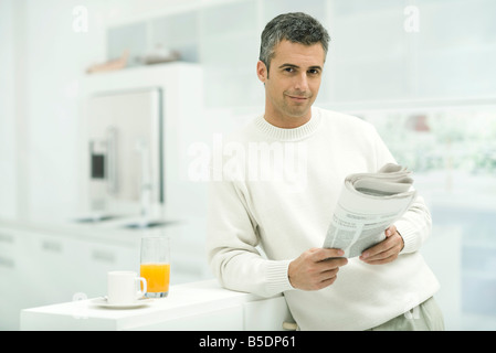 Man leaning against counter on elbows, reading newspaper Stock Photo ...