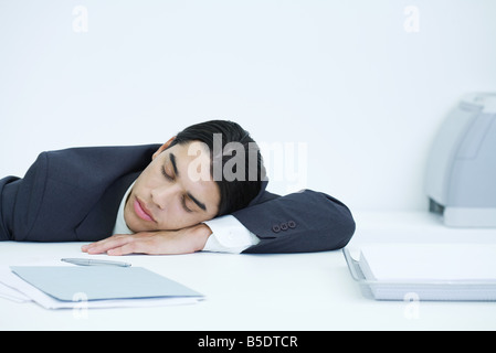 Young businessman slouching on desk, holding head Stock Photo - Alamy
