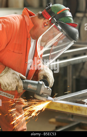 A warehouse worker grinding a corner of a weld with sparks flying Stock ...