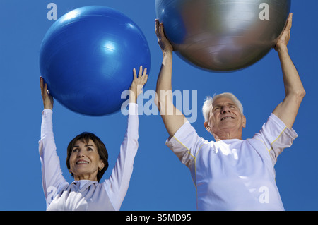 Middle age couple holding yoga mat pointing with hand finger to the ...