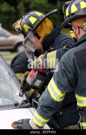 A firefighter cutting the glass windshield out of a car that has rolled ...
