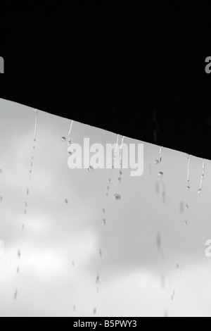 lots rain drops falling off property roof Stock Photo - Alamy
