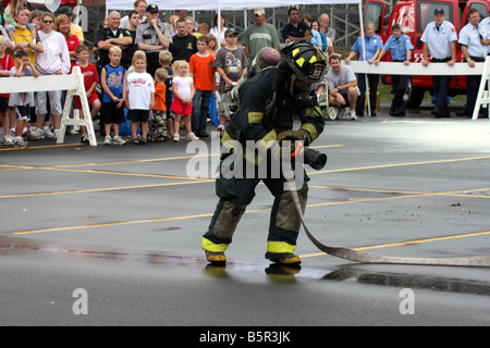 A firefighter getting a hoseline ready at a fire demonstration at a ...