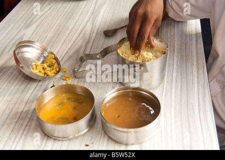 Man eating rice with sambar and vegetable curry from his tiffin box ...