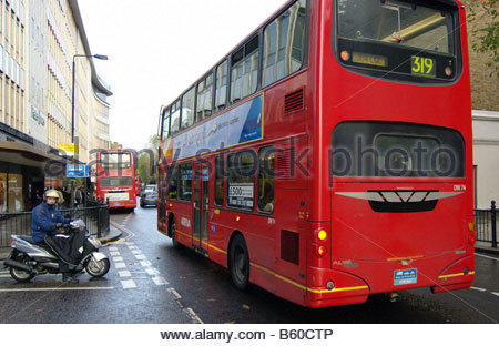 the rear view of a double decker red London bus as it enters a Stock ...
