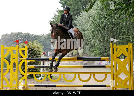 Female show jumper clearing the poles of a Triple Bar Jump during a ...