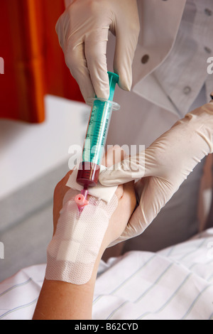 Nurse taking a blood sample from arm vein with a vacutainer ...