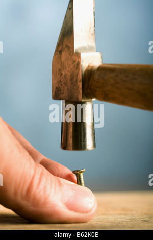 Human hand with hammer hitting nail in wall Stock Photo - Alamy