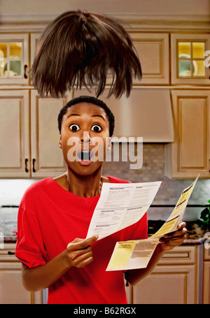 Shocked black woman holding papers and gesturing at home Stock Photo ...