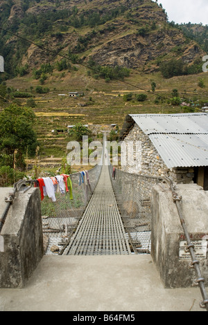 Metal rope bridge crossing the Modi river valley in the Annapurna range ...