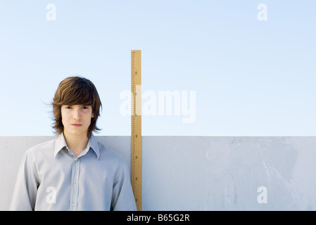 Young man measuring his height with ruler Stock Photo - Alamy