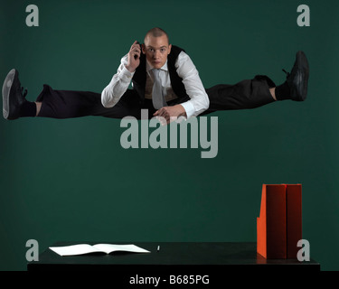 Business man jumping over desk Stock Photo - Alamy