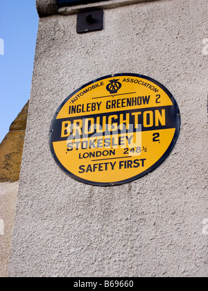 Old yellow and black AA distance sign fixed to house wall at Newent ...