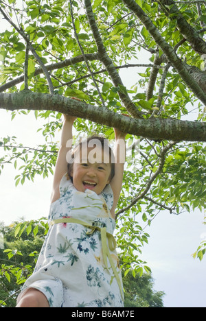 Girl hanging from tree Stock Photo - Alamy
