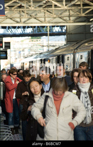 Passengers getting off of a train onto a crowded railway station ...
