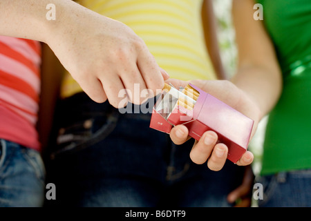 Underage smoking. Young teenage girl taking a cigarette from her Stock ...