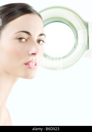 Skin examination. Woman's face beside a dermatological lamp. She is 21 ...