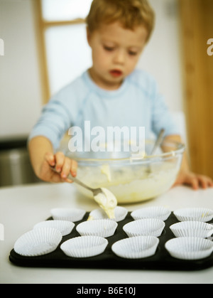 Boy spooning cake mixture into cake cases Stock Photo - Alamy