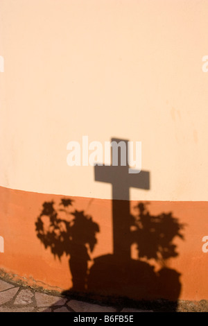The shadow of a church cross cast on a gable in light yellow with a ...
