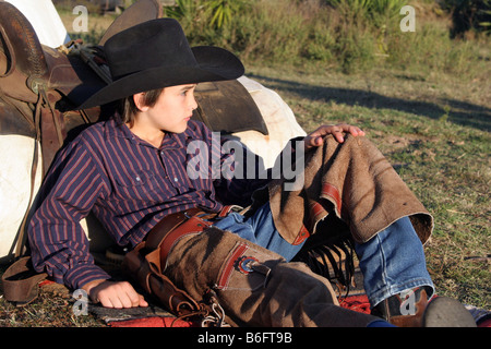 A young cowboy resting against his bed roll out on the range Stock ...