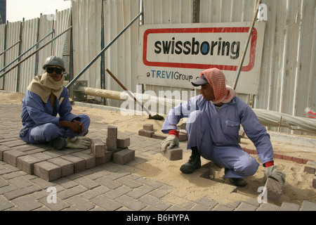Migrant workers laying bricks for pavement in Doha, Qatar Stock Photo ...