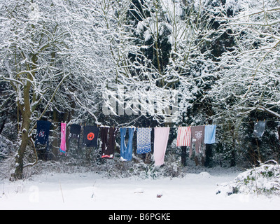 Frozen clothes hanging from a washing line in a snow-covered garden in ...