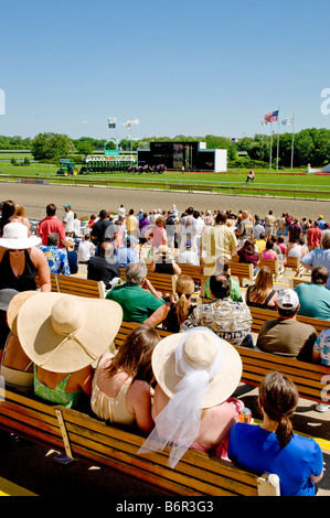 Female horse racing fans wearing hats watching the start of a turf race ...