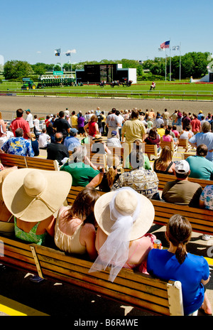Female horse racing fans wearing hats watching the start of a turf race ...