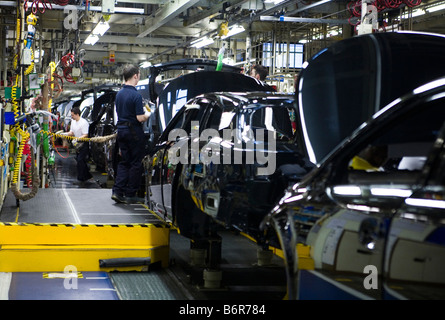 A worker at Toyota Final Assembly production line fits a part to a ...
