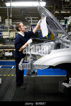 A worker at Toyota Final Assembly production line fits a part to a ...