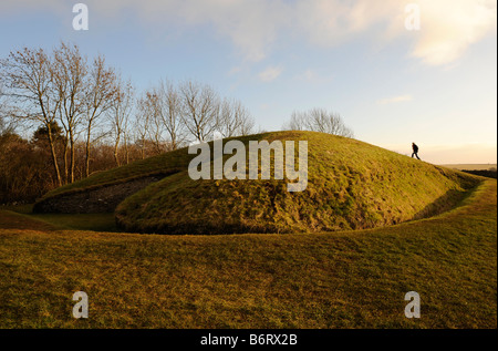 A walker passes the Stone Age long barrow of Belas Knapp near ...