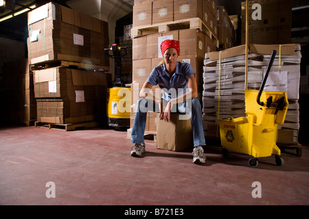 Female janitor in warehouse next to cartons Stock Photo - Alamy