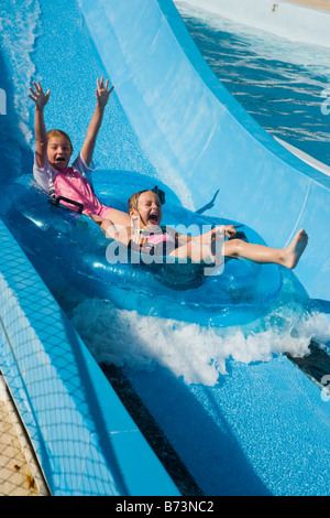 Portrait of girls sliding down waterslide together on innertube in ...