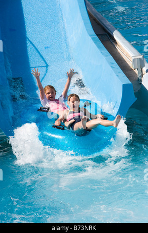 Girls sliding down waterslide on innertube in water park Stock Photo ...