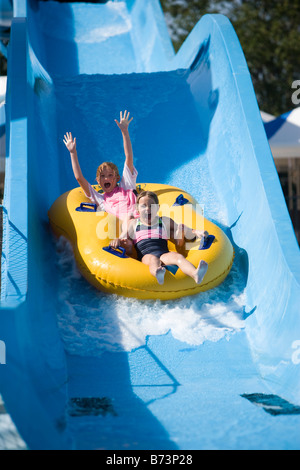 Girls sliding down waterslide on innertube in water park Stock Photo ...