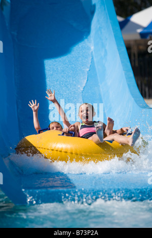 Girls sliding down waterslide on innertube in water park Stock Photo ...