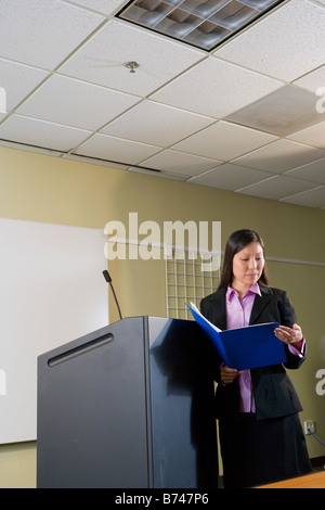 A woman in a suit standing at a lectern Stock Photo - Alamy